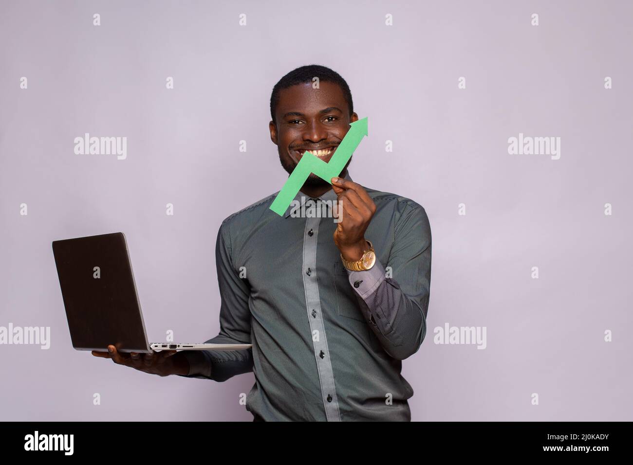 Black man holding laptop and an upward graph symbol marking progress ...