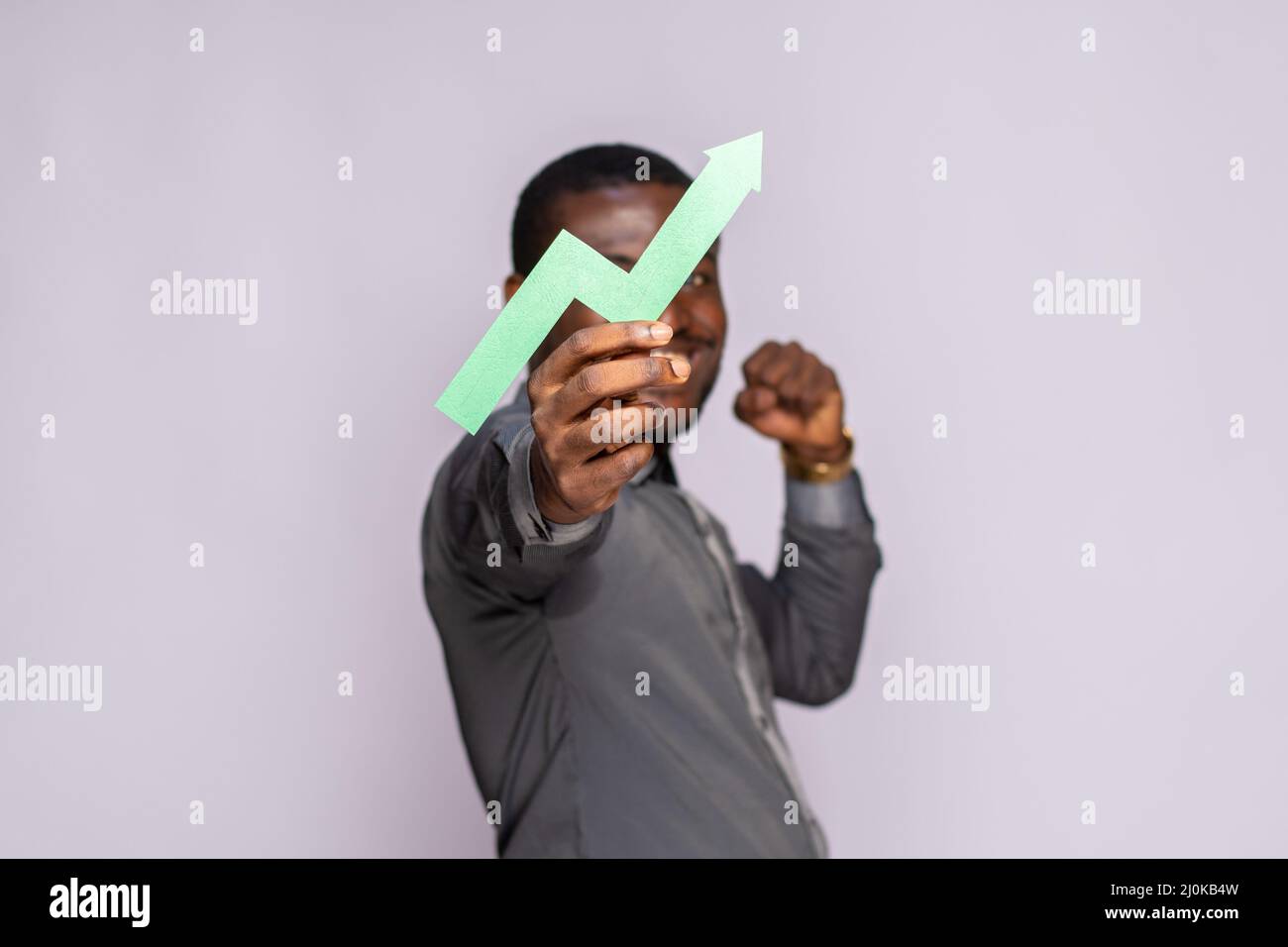 Excited African man holding an upward graph symbol and showing victory ...