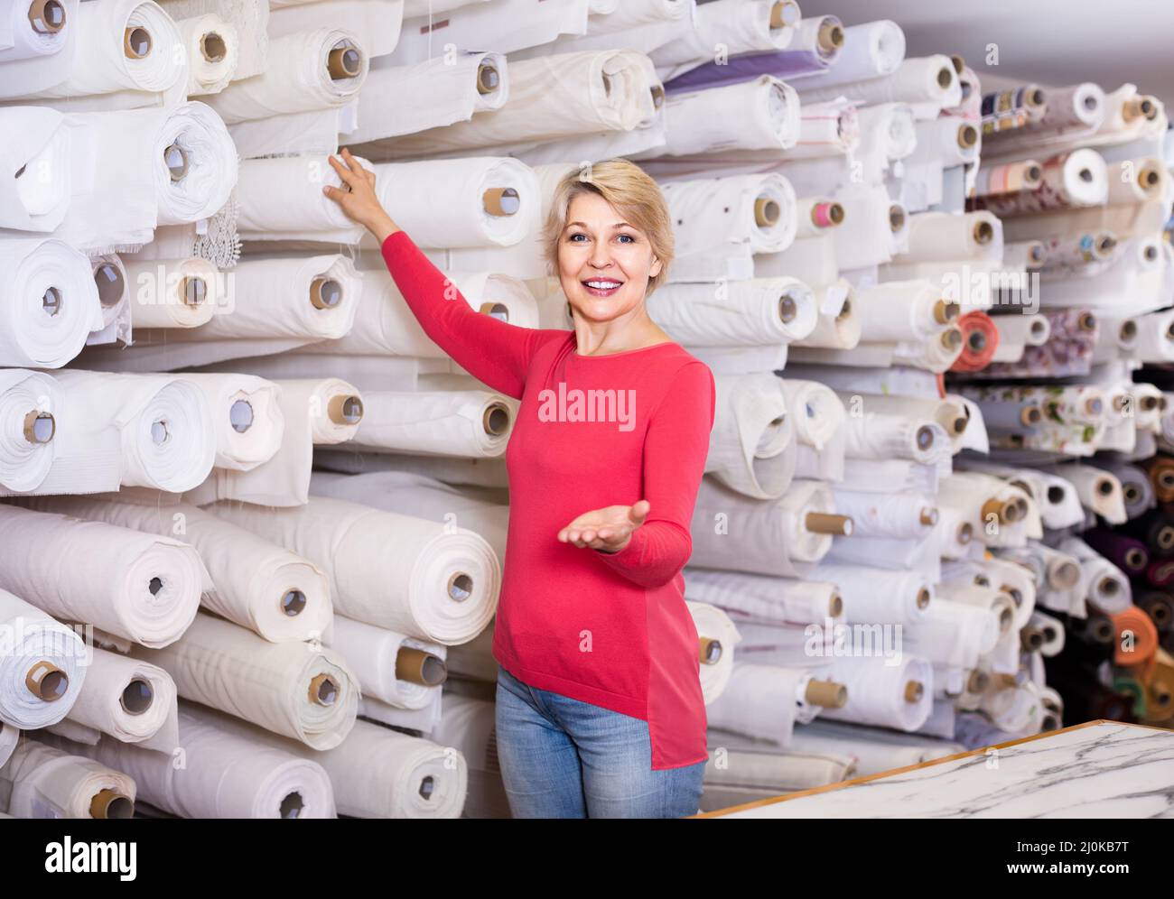 Female shop assistant demonstrating assortment at textile shop Stock ...