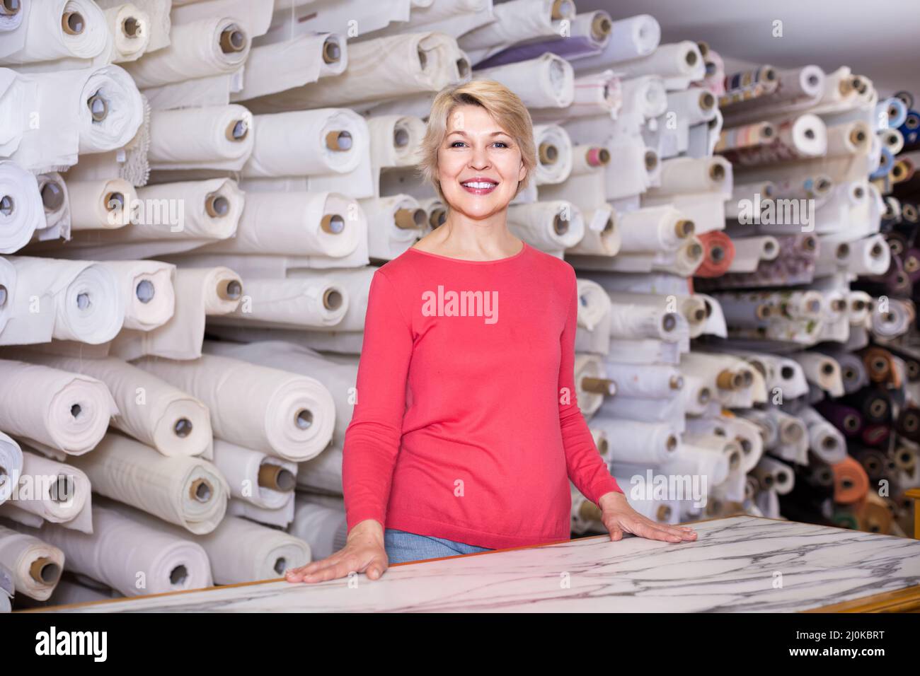 Female shop assistant demonstrating assortment at textile shop Stock ...