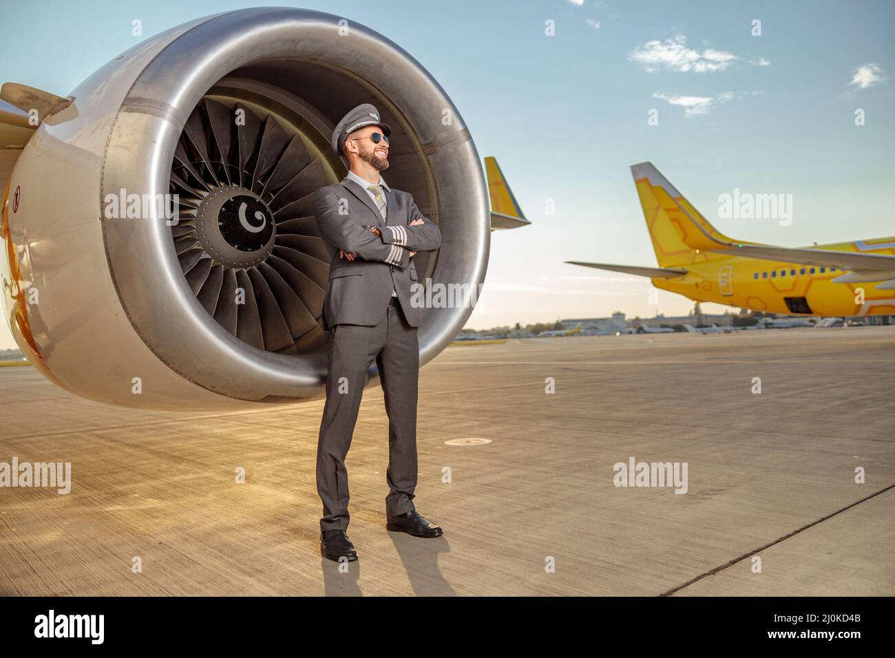 Cheerful airline captain standing near turbine engine at airport Stock ...