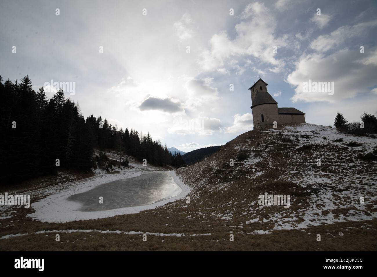 Small ancient church on the top of a small snowy hill in winter under a ...