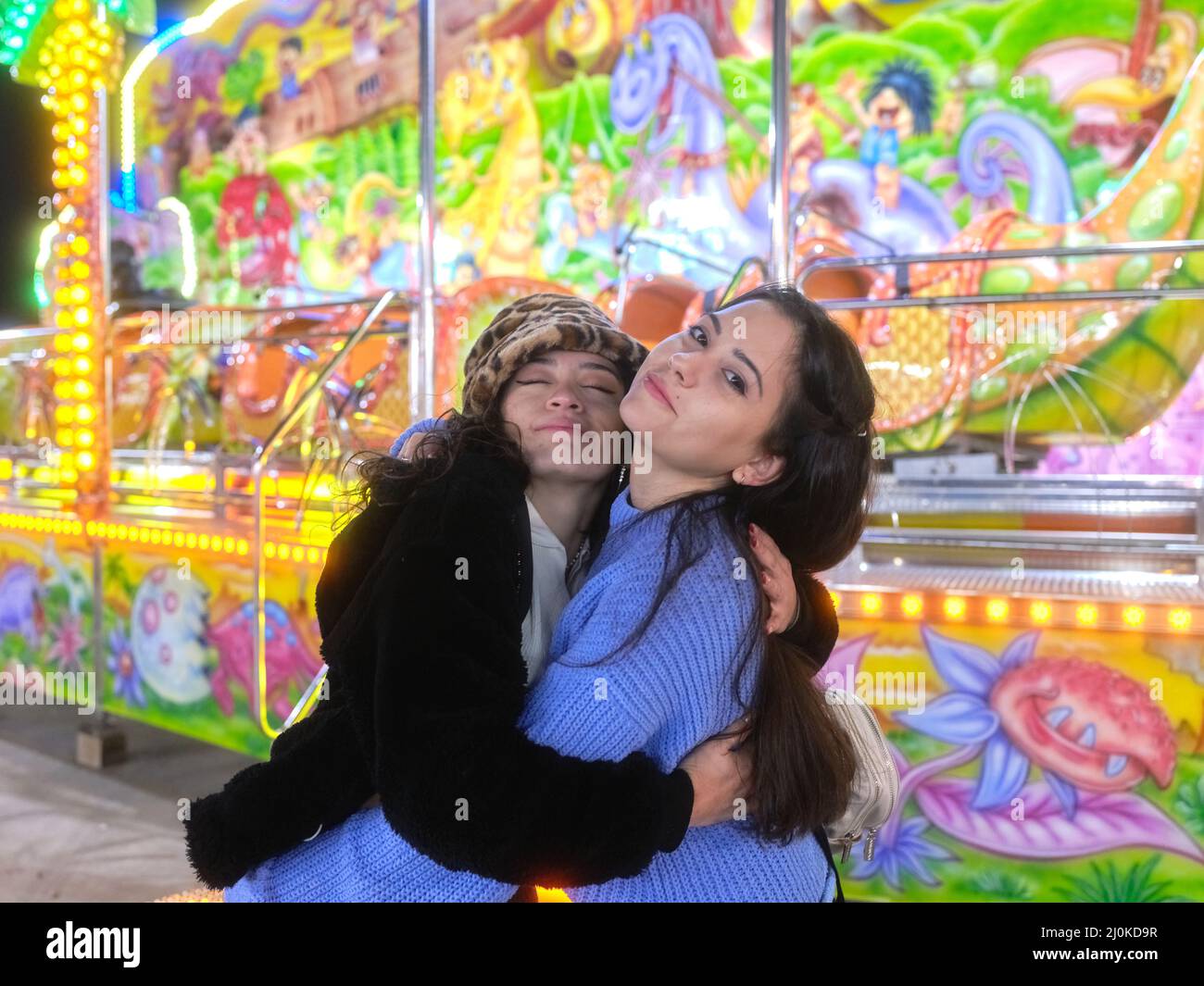 Two friends embracing each other while facing the camera in a night ...