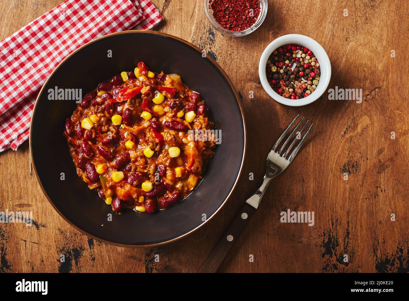 Chili Con Carne with ground beef, beans and corn in dark bowl on wooden ...