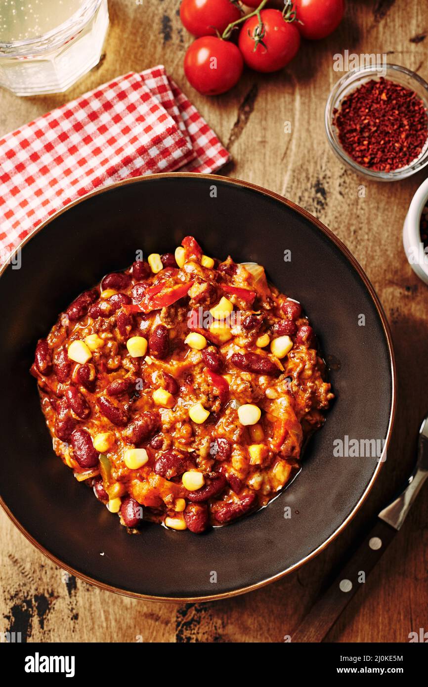 Chili Con Carne with ground beef, beans and corn in dark bowl on wooden ...