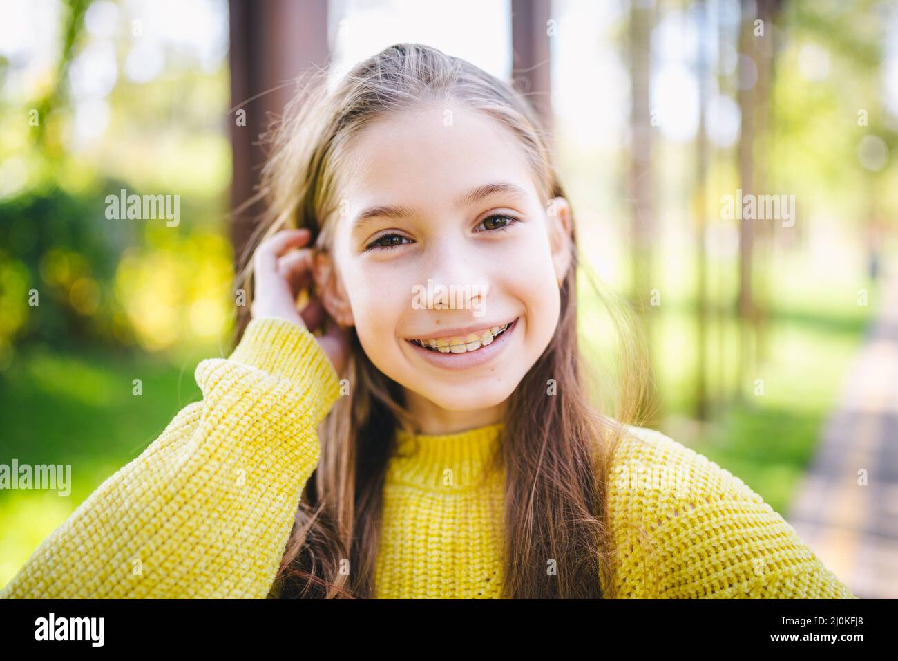 Cute and happy teen girl with braces smiling to camera in yellow ...