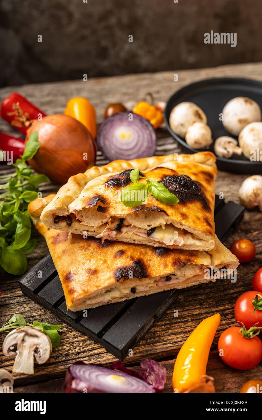 Sliced pizza calzone served on tha black palette Stock Photo - Alamy