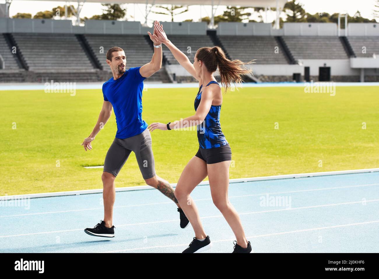 Good job. Full length shot of two young athletes high fiving while ...
