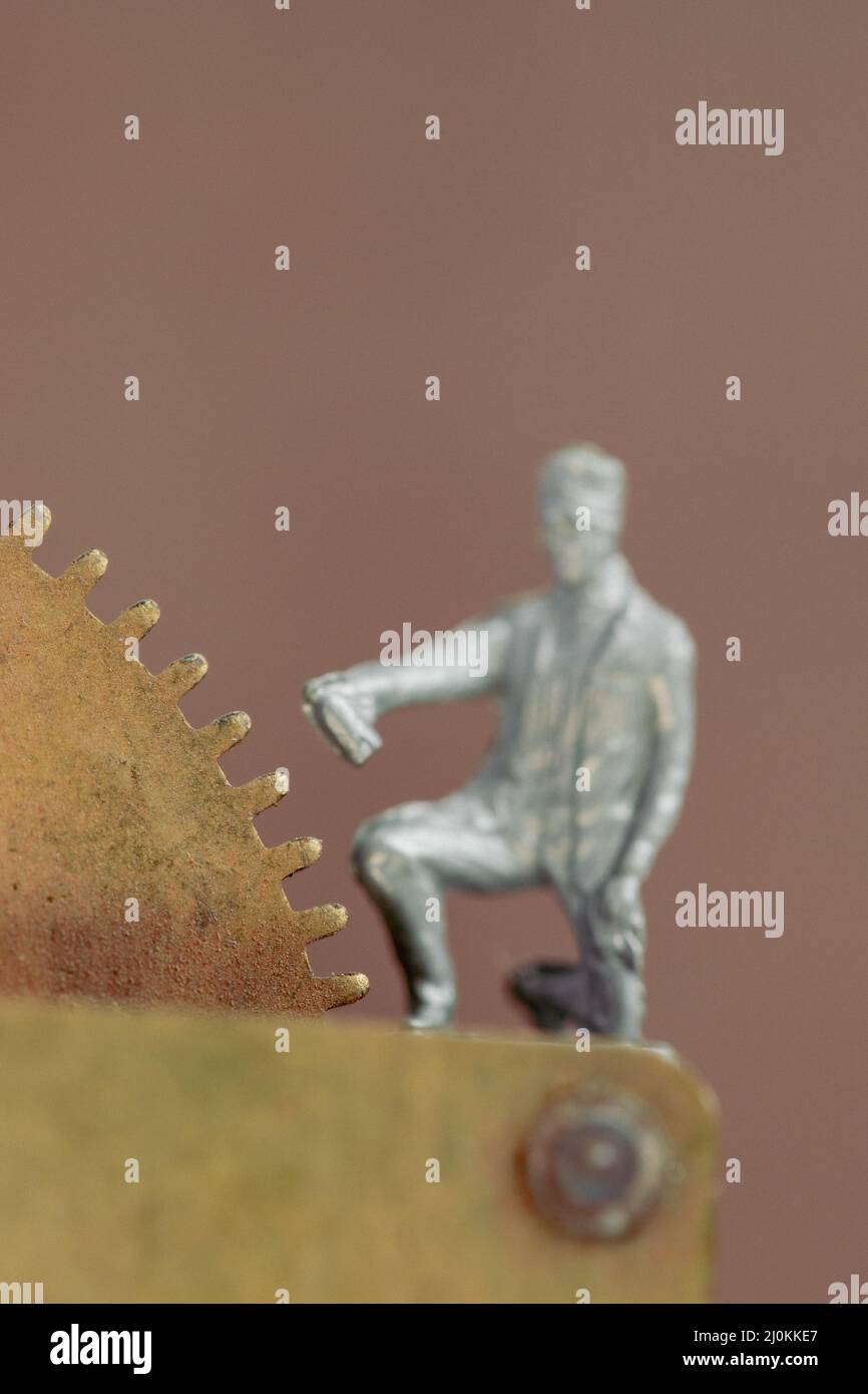 Macro of clock parts with a old cast iron railroad worker in background ...