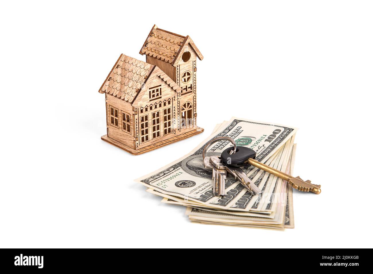 house keys lying on a wad of money and a wooden house behind, on a ...