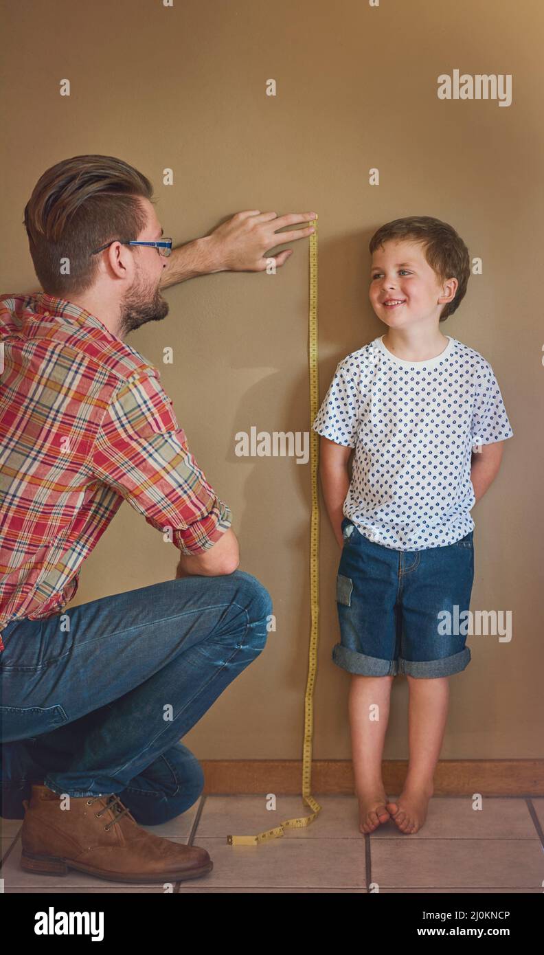 Look how much youve grown. Shot of a father measuring his little boys ...