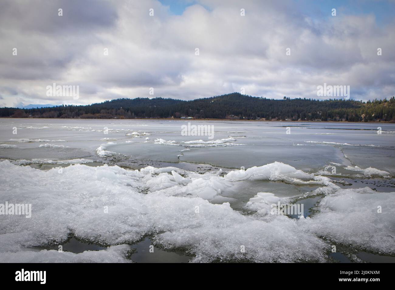 Snow is layered in clumps on a frozen yet slowly melting Hauser Lake in ...