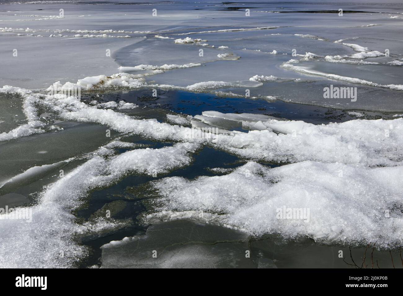 Snow is layered in clumps on a frozen yet slowly melting Hauser Lake in ...