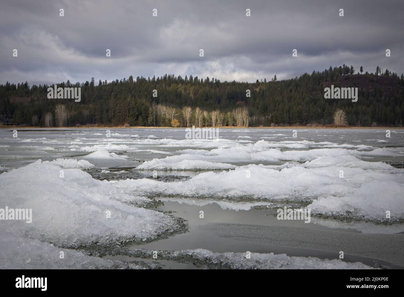 Snow is layered in clumps on a frozen yet slowly melting Hauser Lake in ...