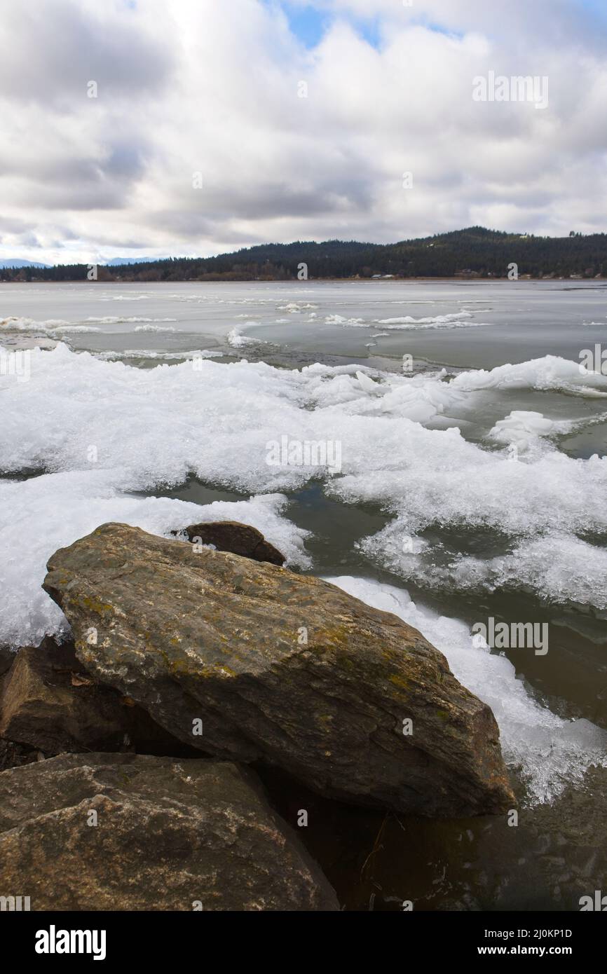 Snow is layered in clumps on a frozen yet slowly melting Hauser Lake in ...