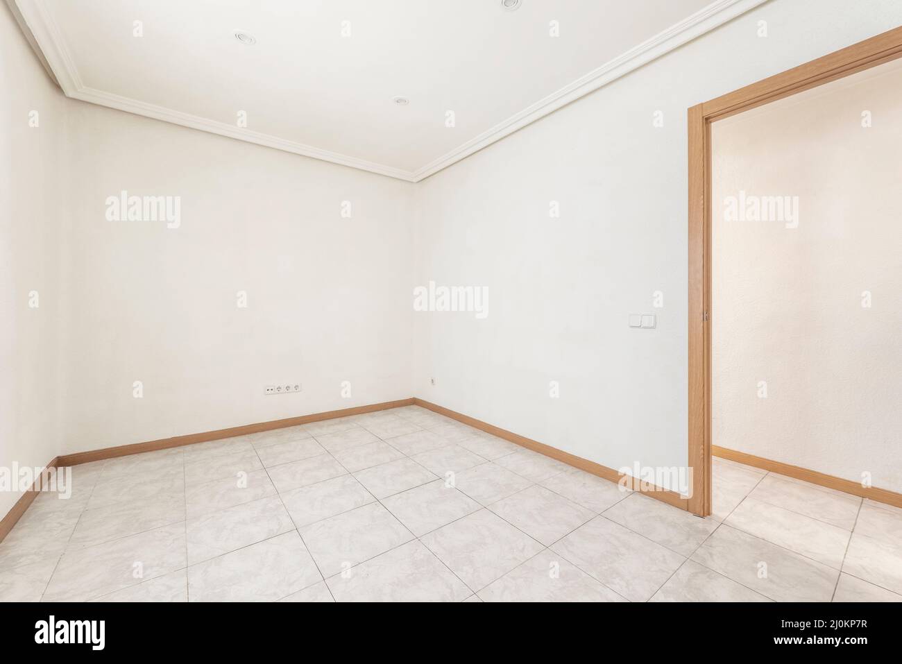 Empty room with light stoneware floor, oak carpentry in baseboards and ...