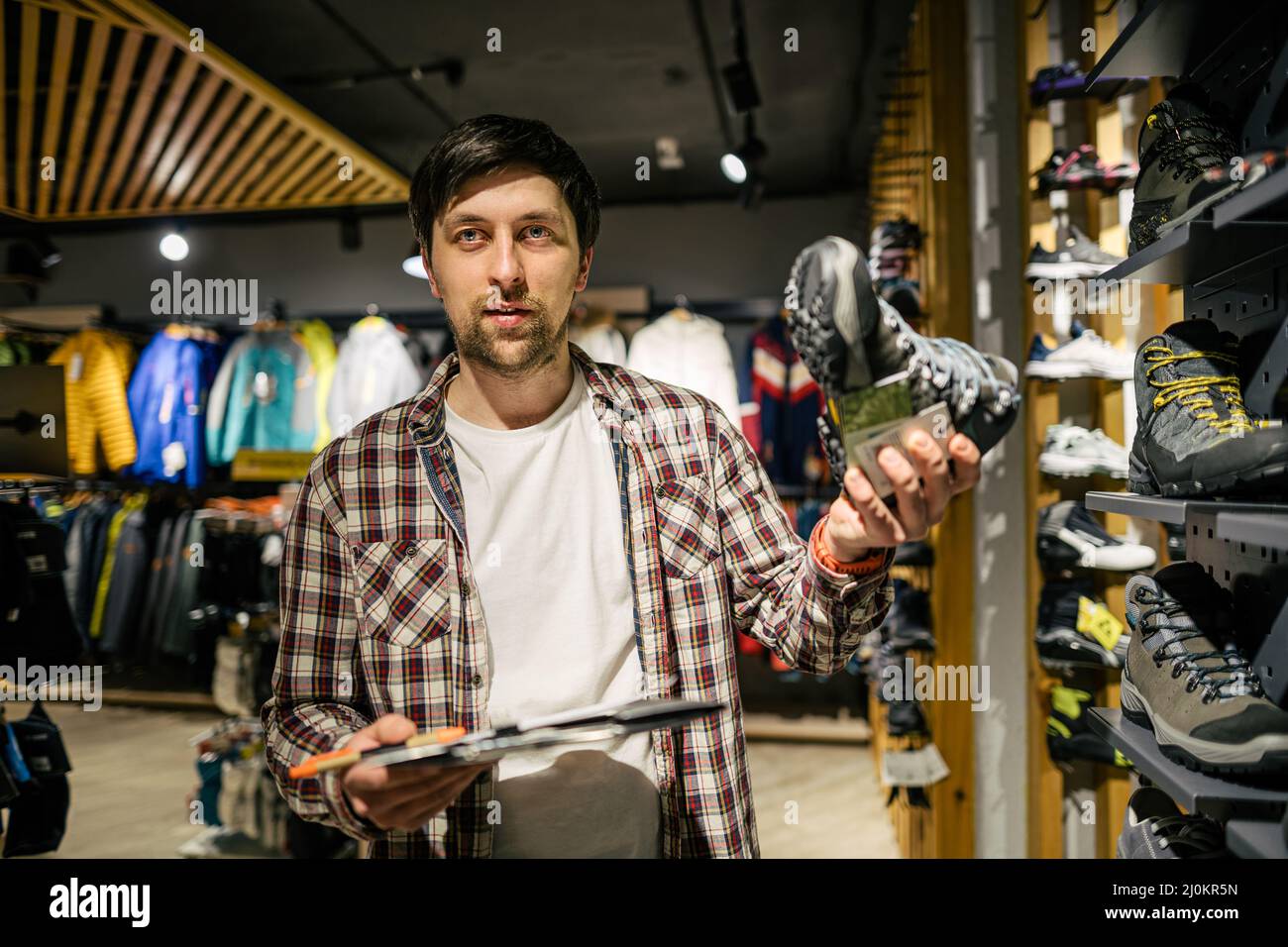 Store clerk helping customer try hiking boots at outdoors equipment ...