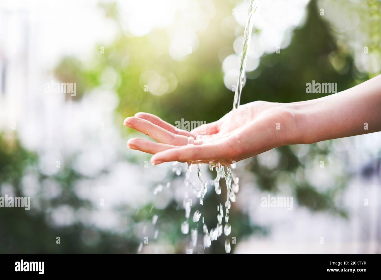 Water cascades. Shot of hands held out to catch a stream of water ...