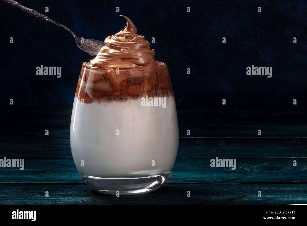 Dalgona cold with a spoon and a place for text, on a dark background ...