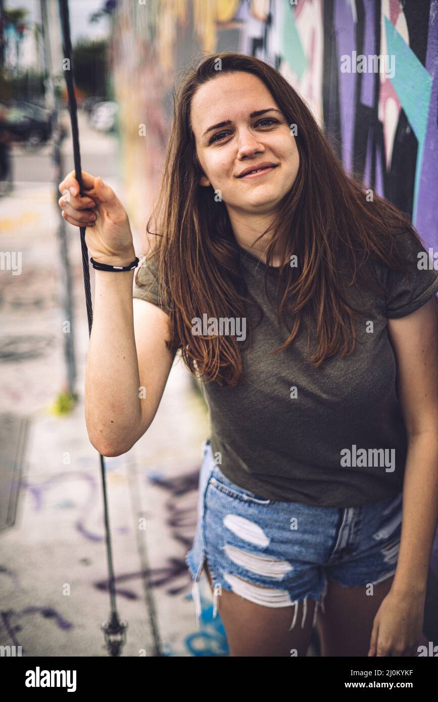 Young and beautiful woman leans against a colorful wall and poses for ...