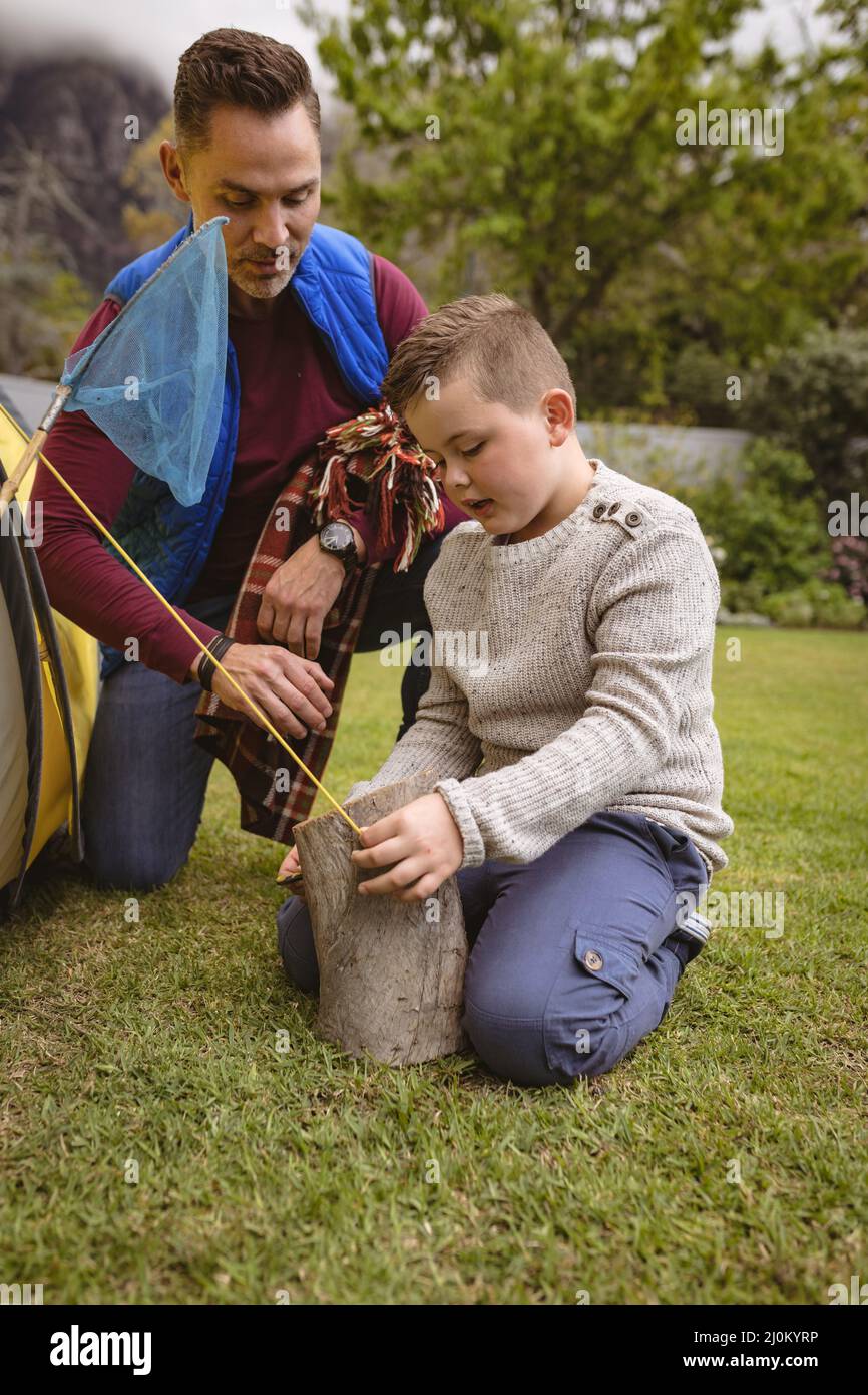 Caucasian father watching while his son setting up a tent in the garden ...