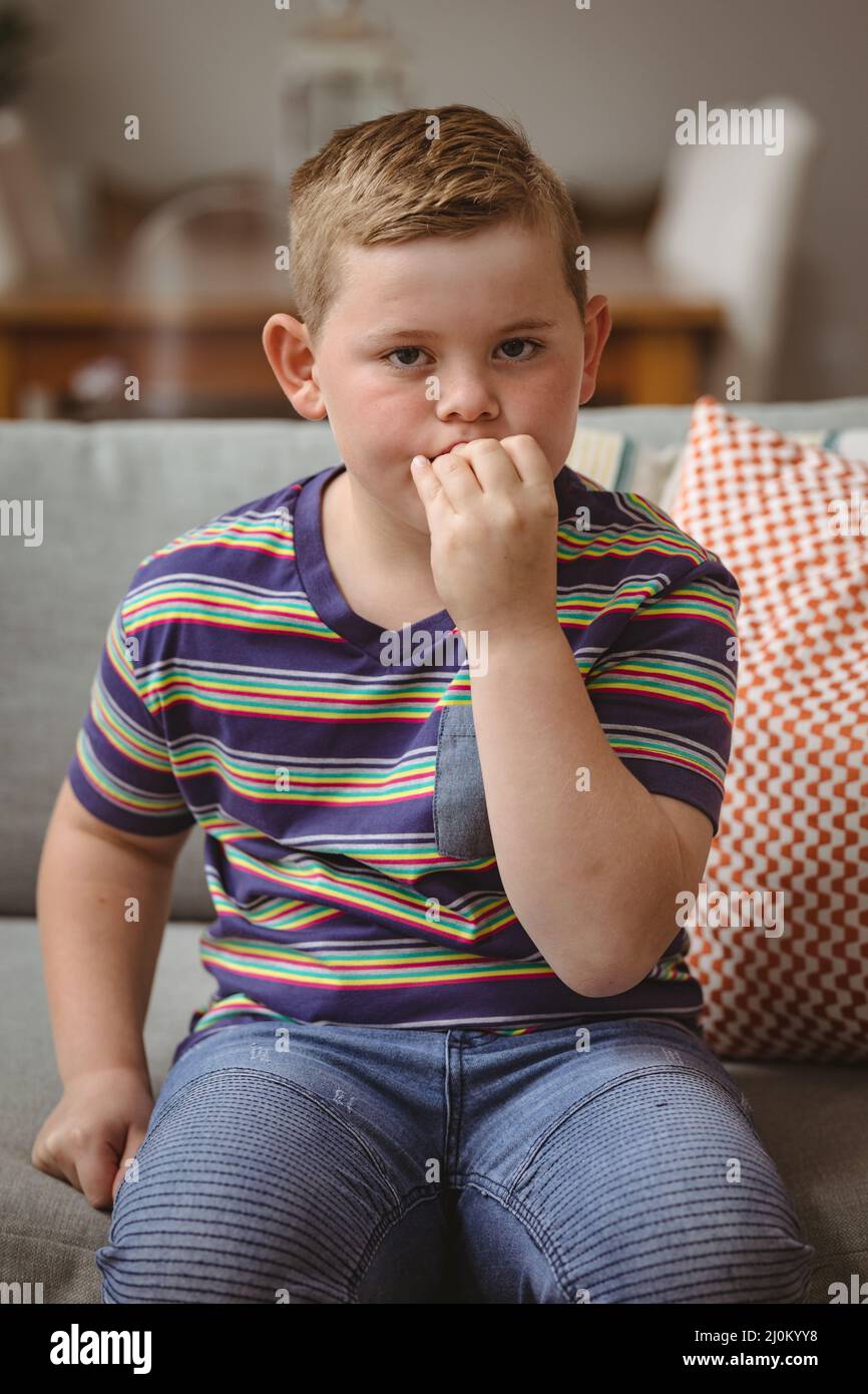 Portrait of caucasian boy making hand gestures sitting on the couch at ...
