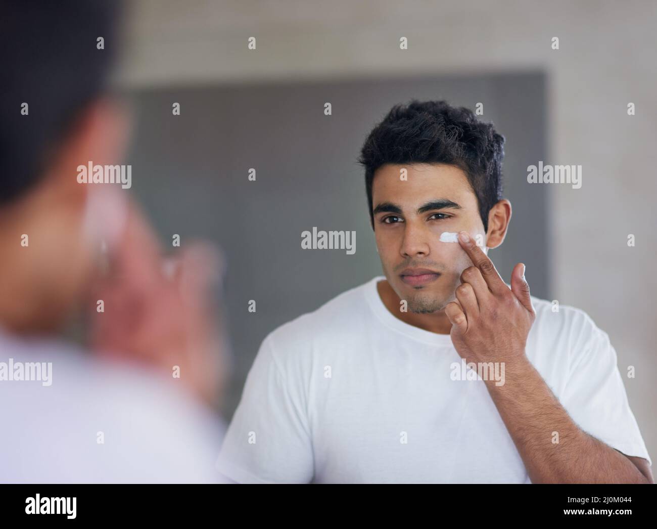 The best skincare product for maximum moisturising. Shot of a handsome young man applying ...