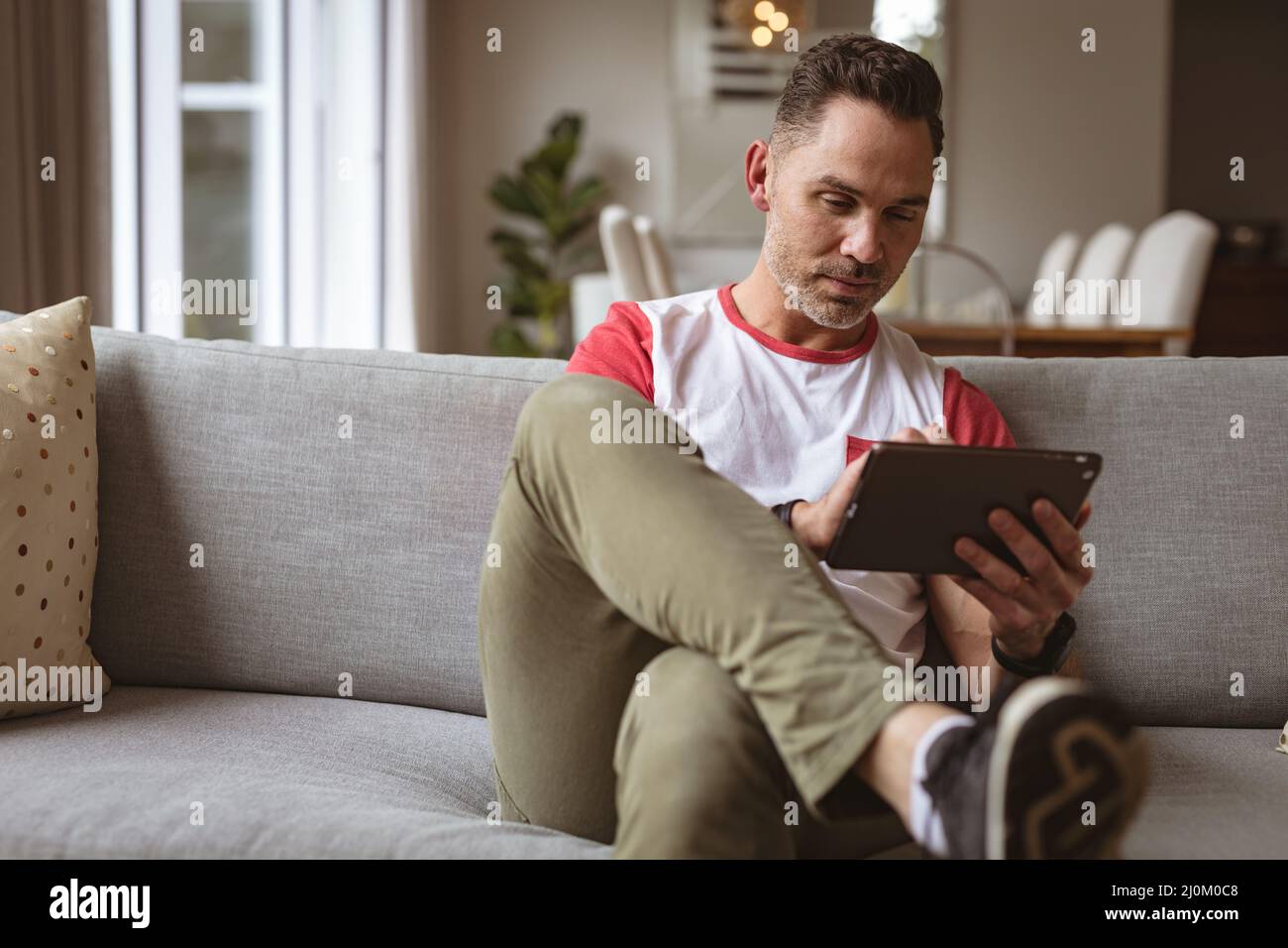 Caucasian man using digital tablet sitting on the couch at home Stock ...