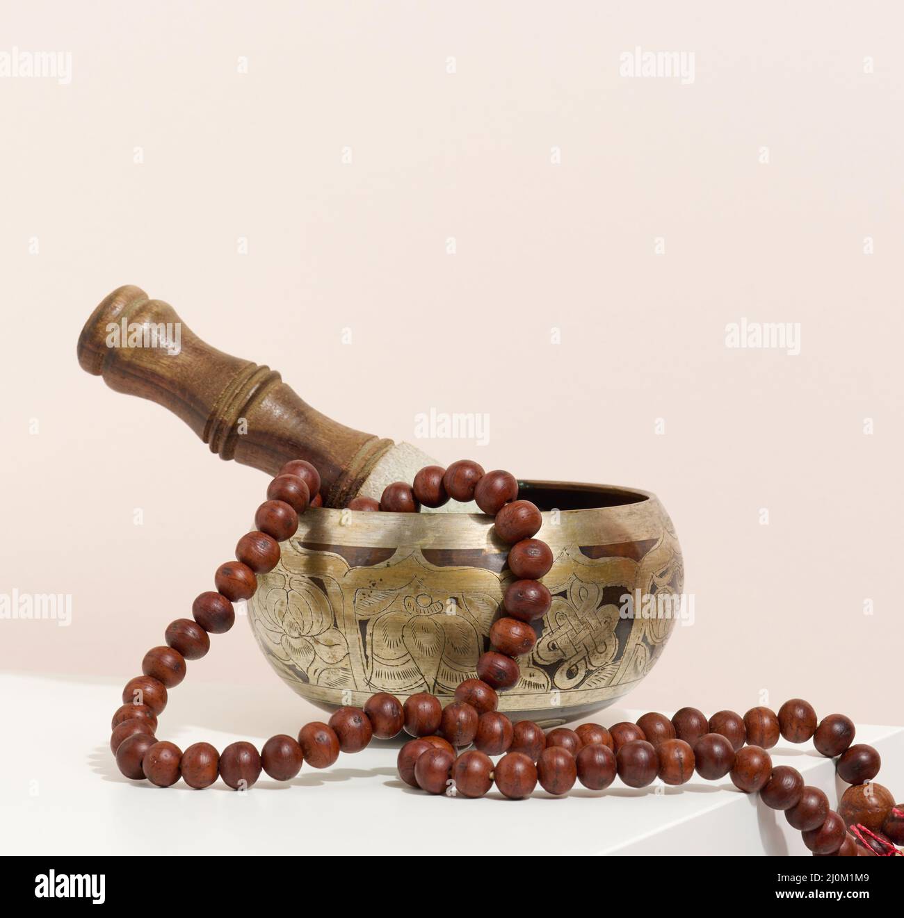 Copper singing bowl and wooden clapper on a white table. Musical ...