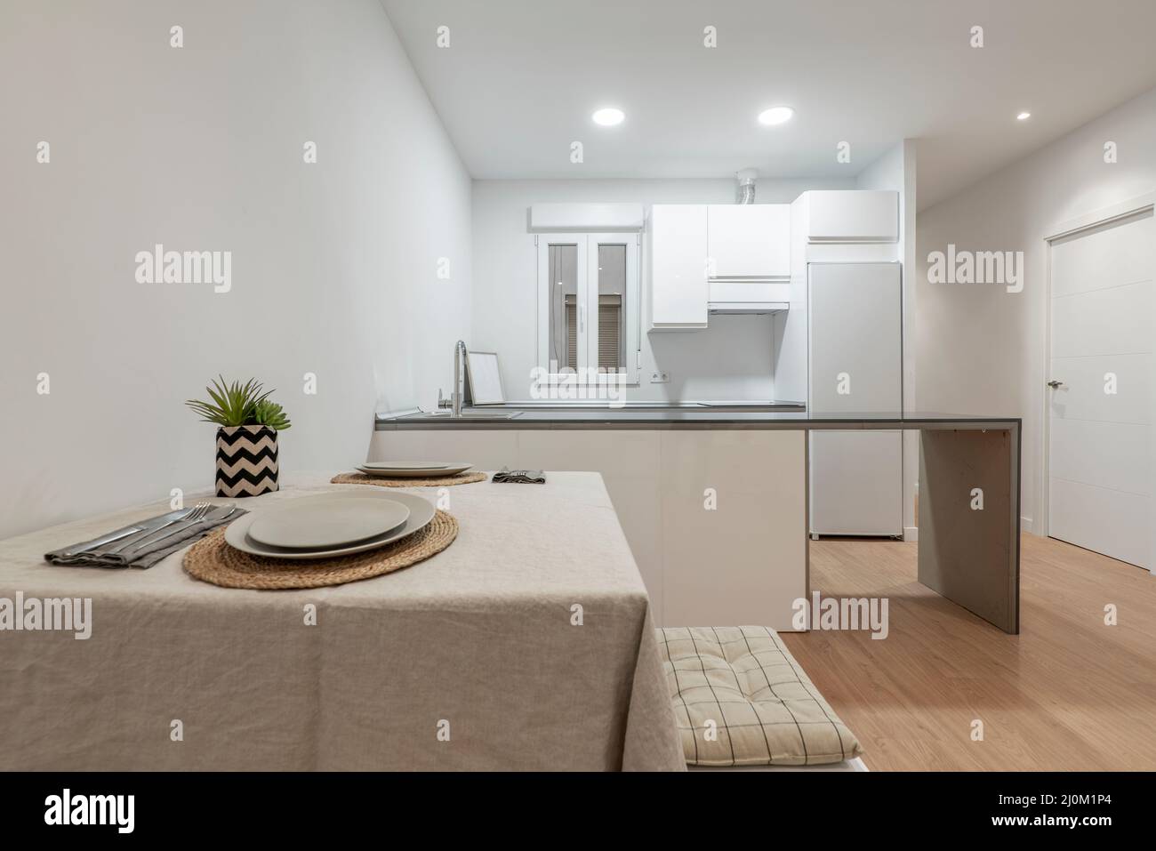 Dining table with tablecloth and food service set up next to a kitchen ...