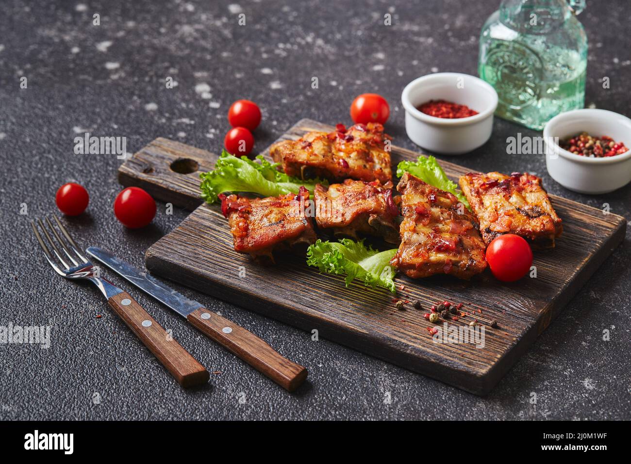 Grilled baked pork ribs with spices and vegetables on wooden cutting ...