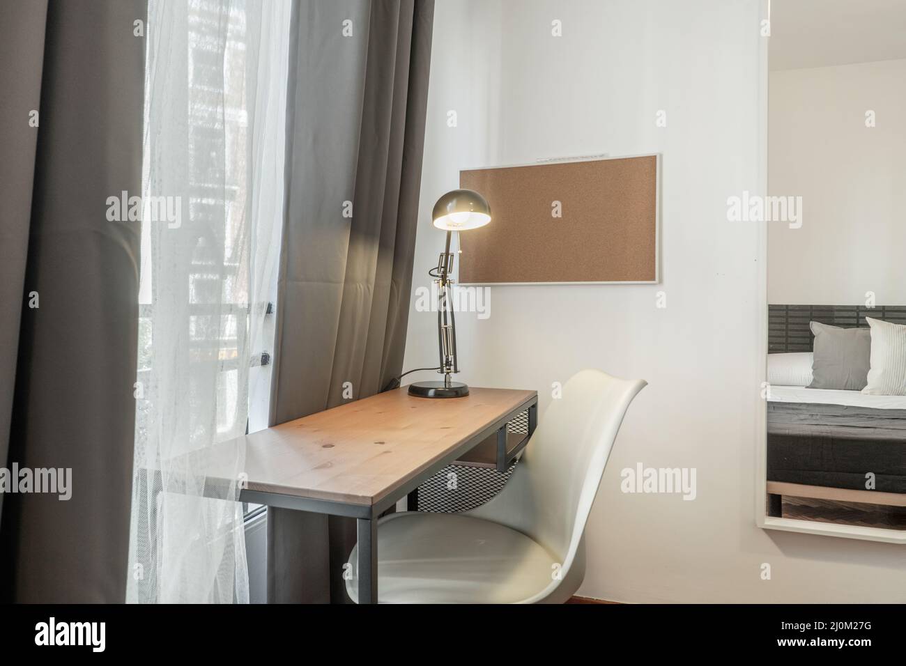 Study tables with a white chair, a black lamp and a mirror on the wall ...