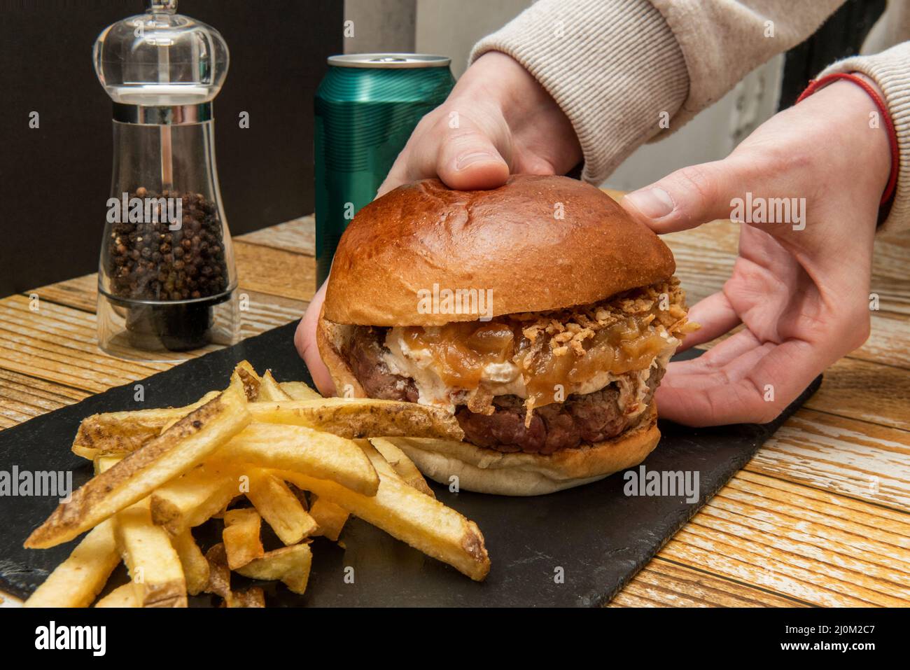 holding in two hands an amazing beef burger with lots of cream cheese ...