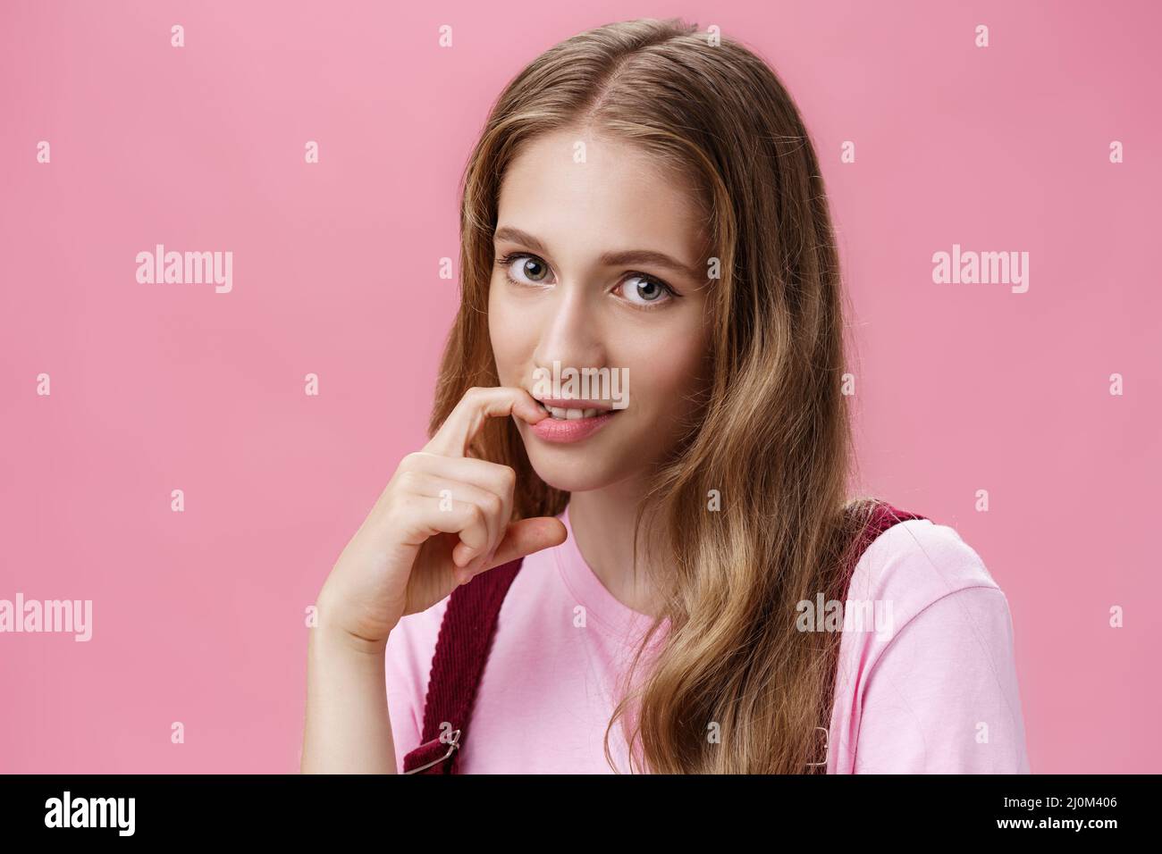 Cute feminine girl learning how make glances and seduce boyfriend with flirty gaze biting finger ...