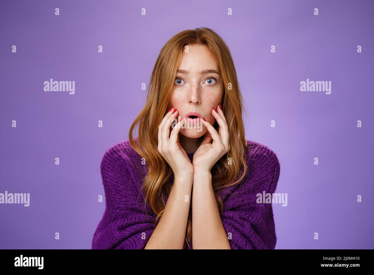 Shocked redhead female friend touching face and open mouth as looking with widen eyes at camera ...