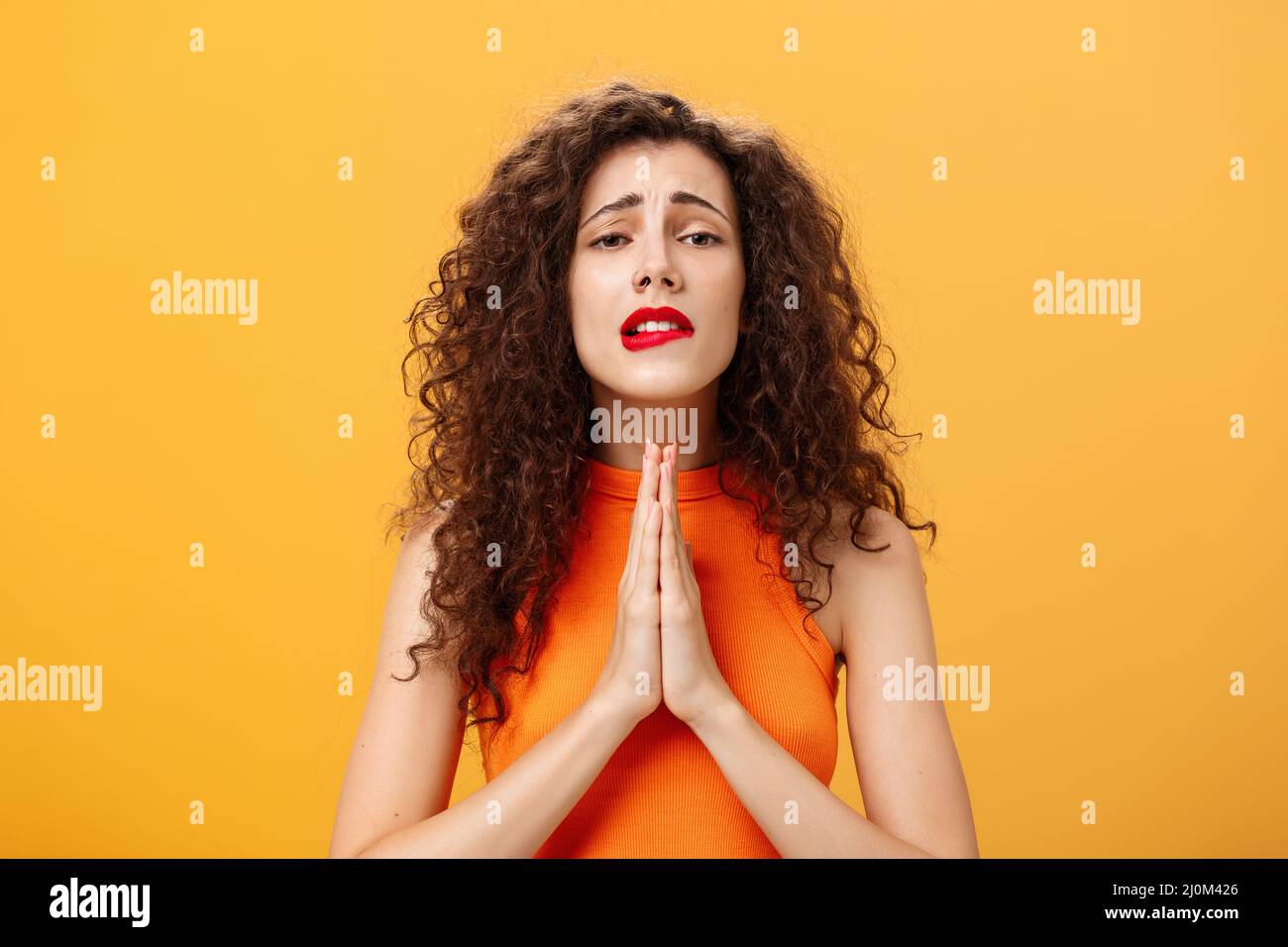 Hopeful charming and silly female with curly haircut holding hands in ...