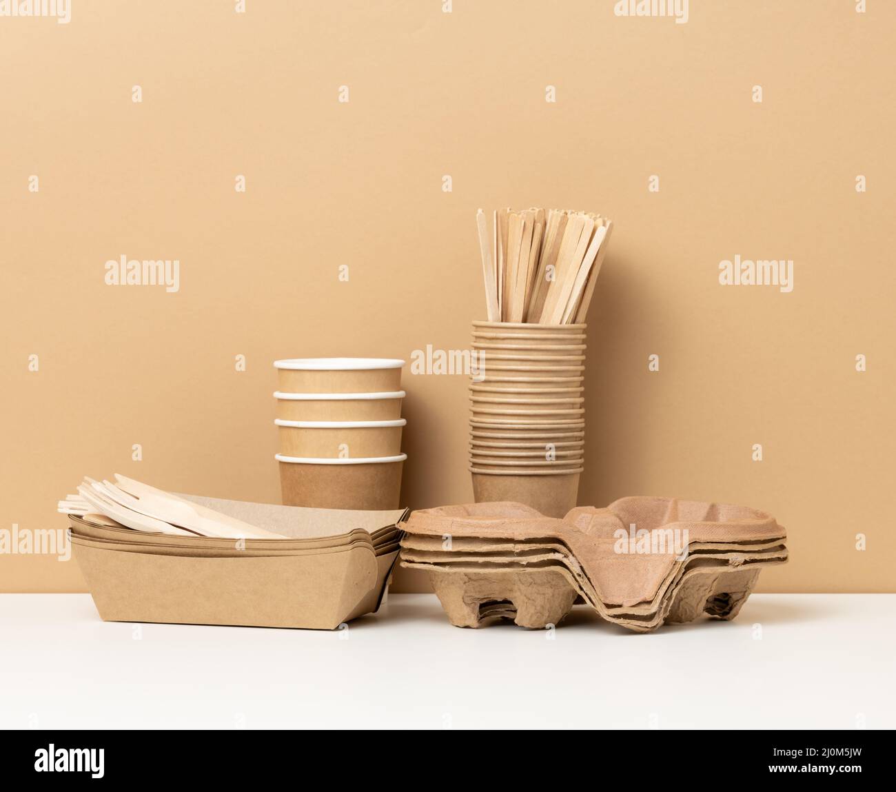 Stack of brown disposable paper cups and a tray on a white table ...