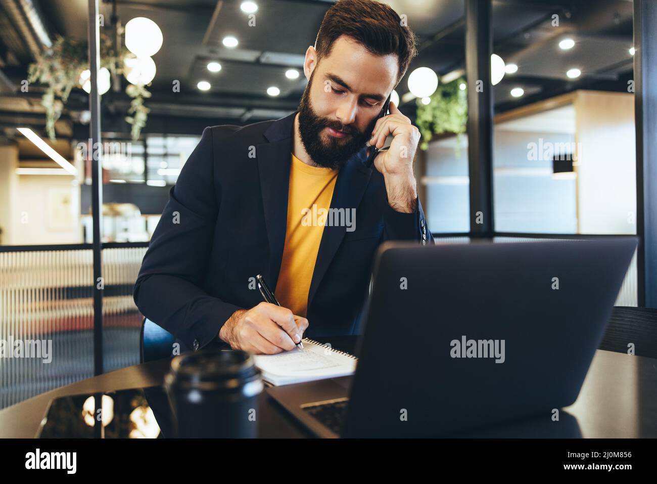 businessman writing notes during a phone call. Young businessman ...