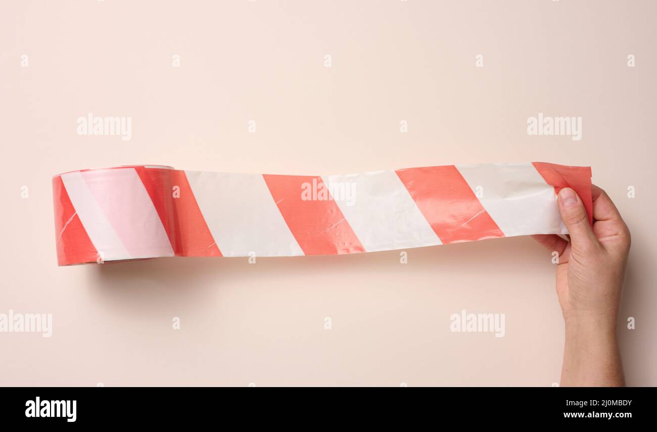 Female hand holding a roll of protective tape on a beige background ...