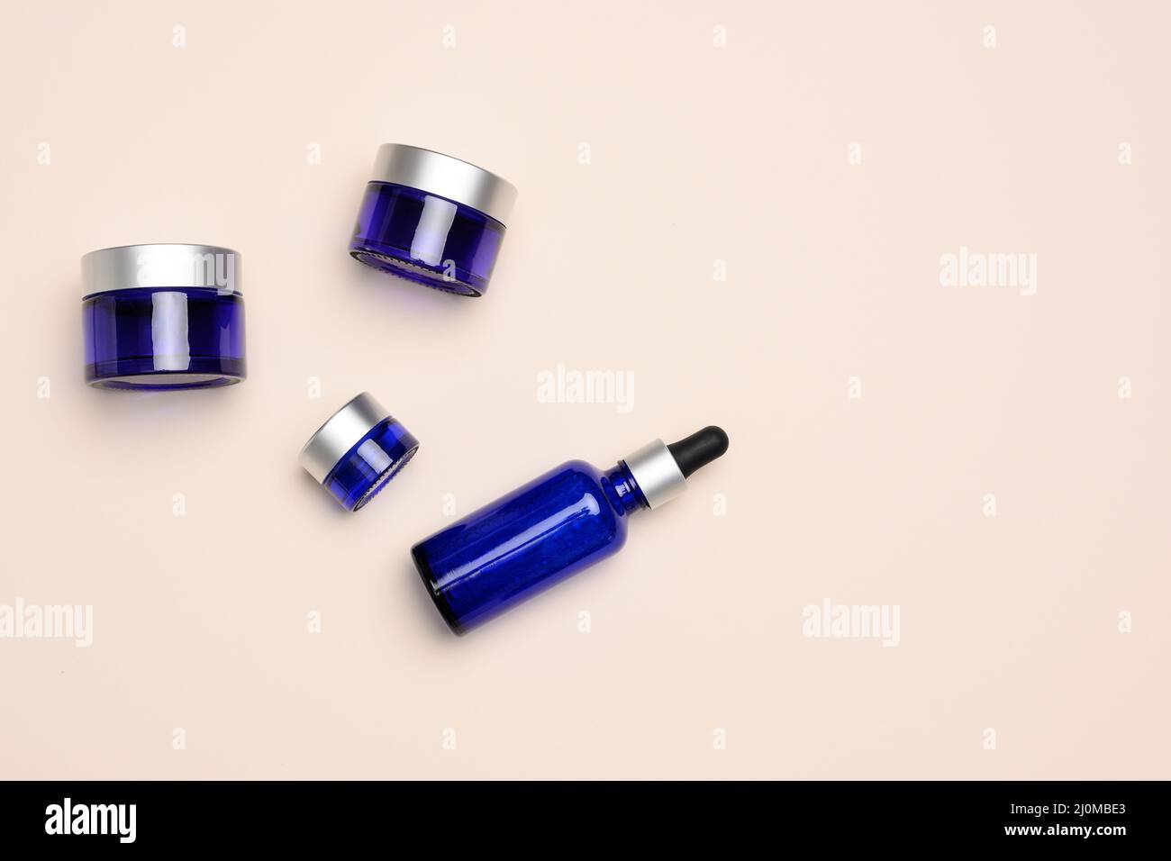 Glass cosmetic blue bottles with a pipette and jar on a beige ...