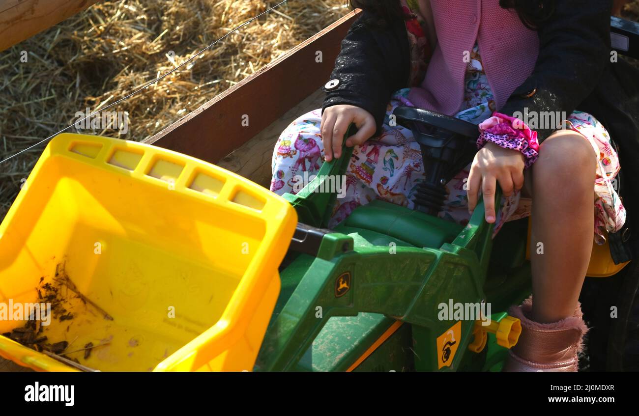 Abstract view of a young girl playing on a a mini digger, Britain, UK ...