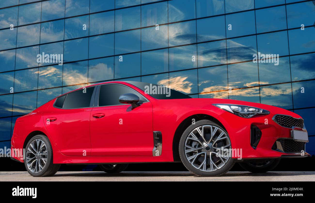 Red car on a blue sky background with white clouds. A stylish, modern ...