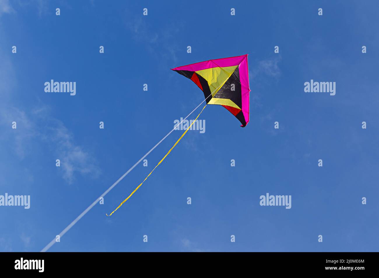 A colorful kite flying high in the bright blue sky Stock Photo - Alamy