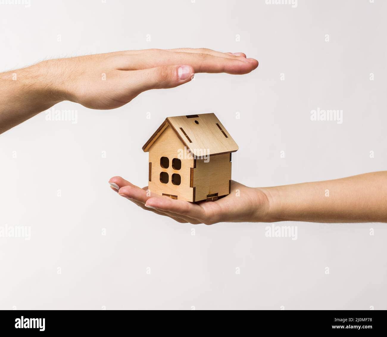 Hands protecting wooden cottage Stock Photo - Alamy