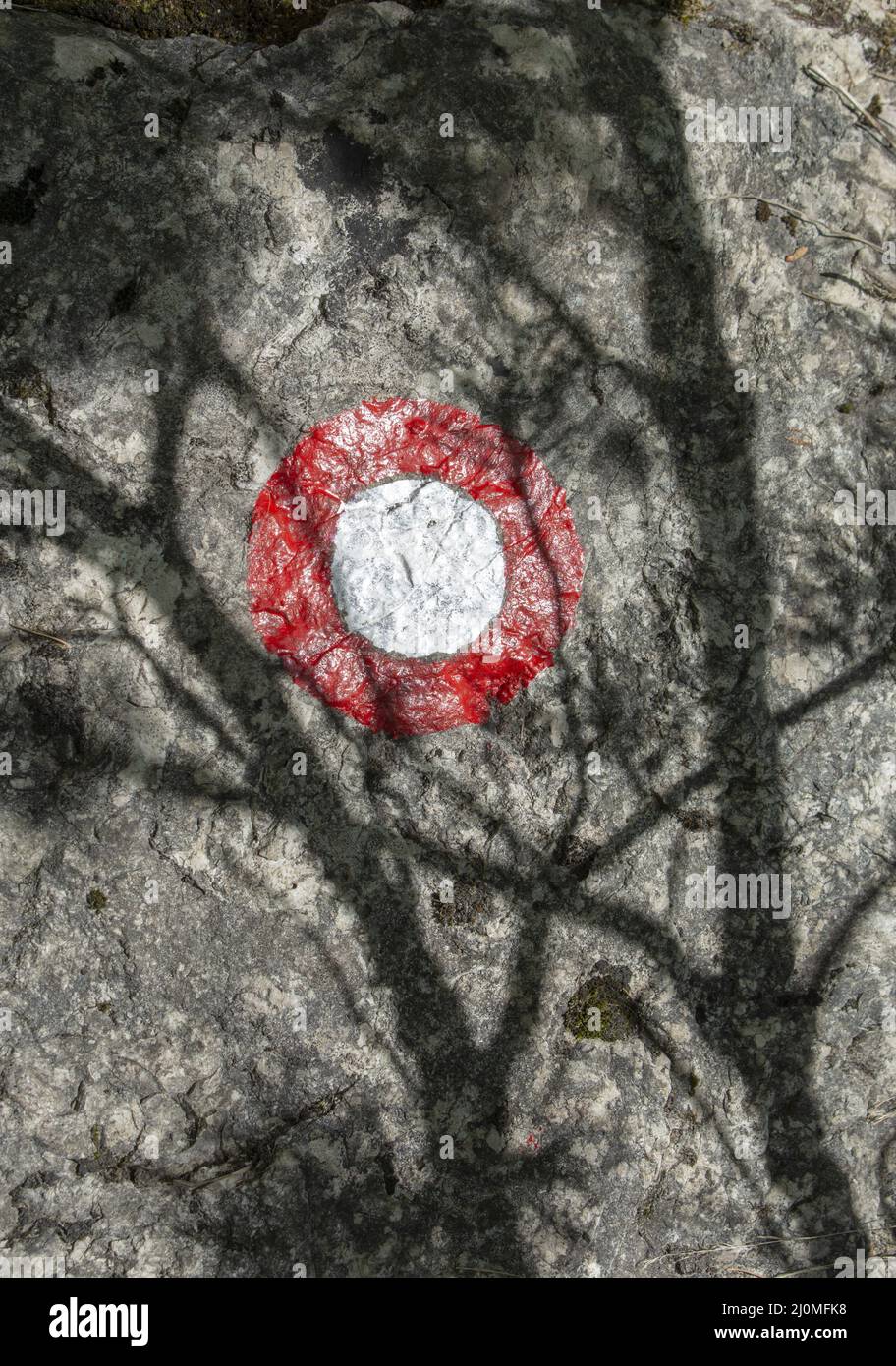 Red and white circle shaped hiking trail sign on a rock wall. Tourist ...
