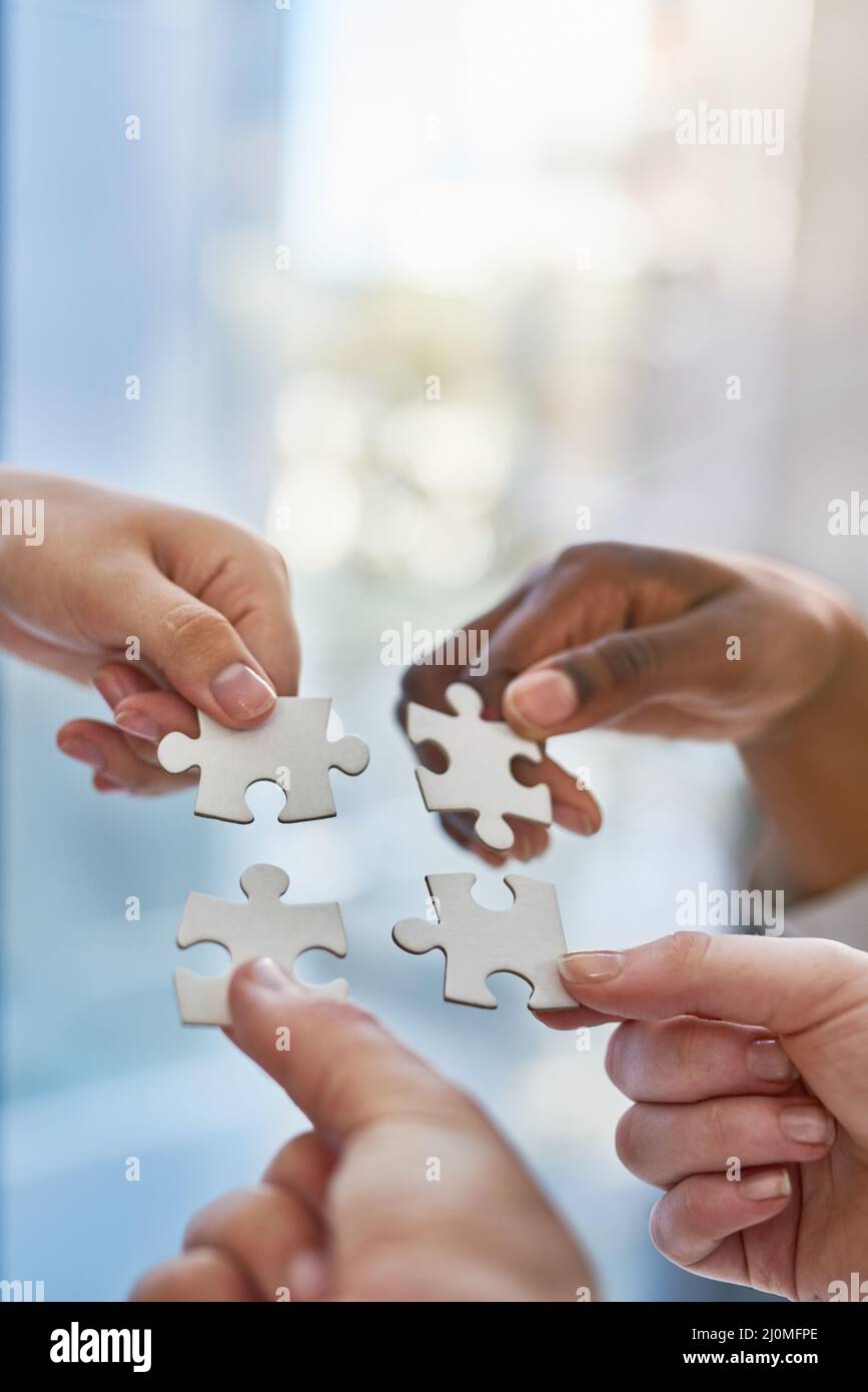 Joining together as a team. Shot of hands putting puzzle pieces ...