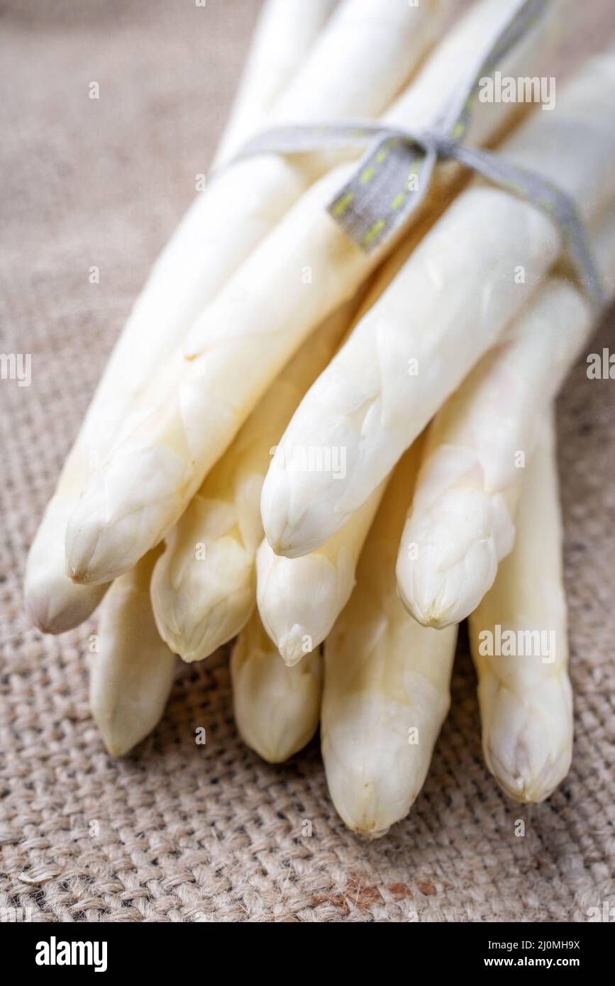 Row white Asparagus offered as close-up on a traditional gunnysack ...