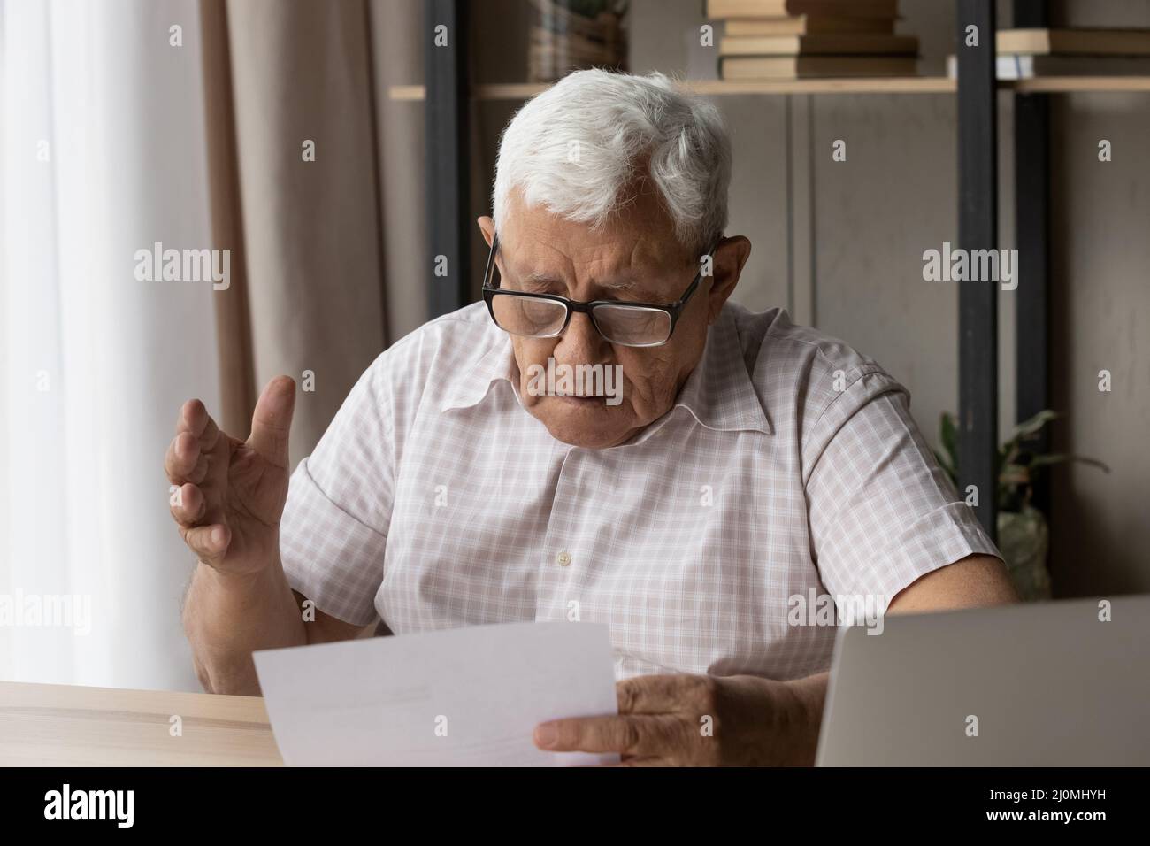 Worried older man read bad news in paper letter Stock Photo - Alamy