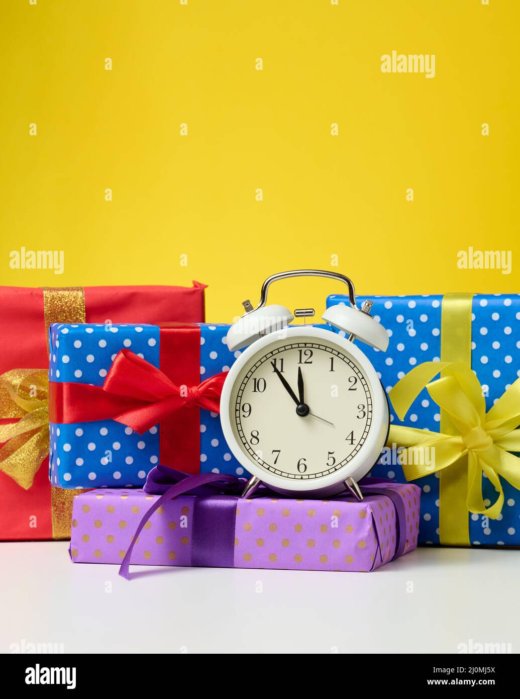 Round alarm clock and a stack of gift boxes tied with a ribbon on a ...