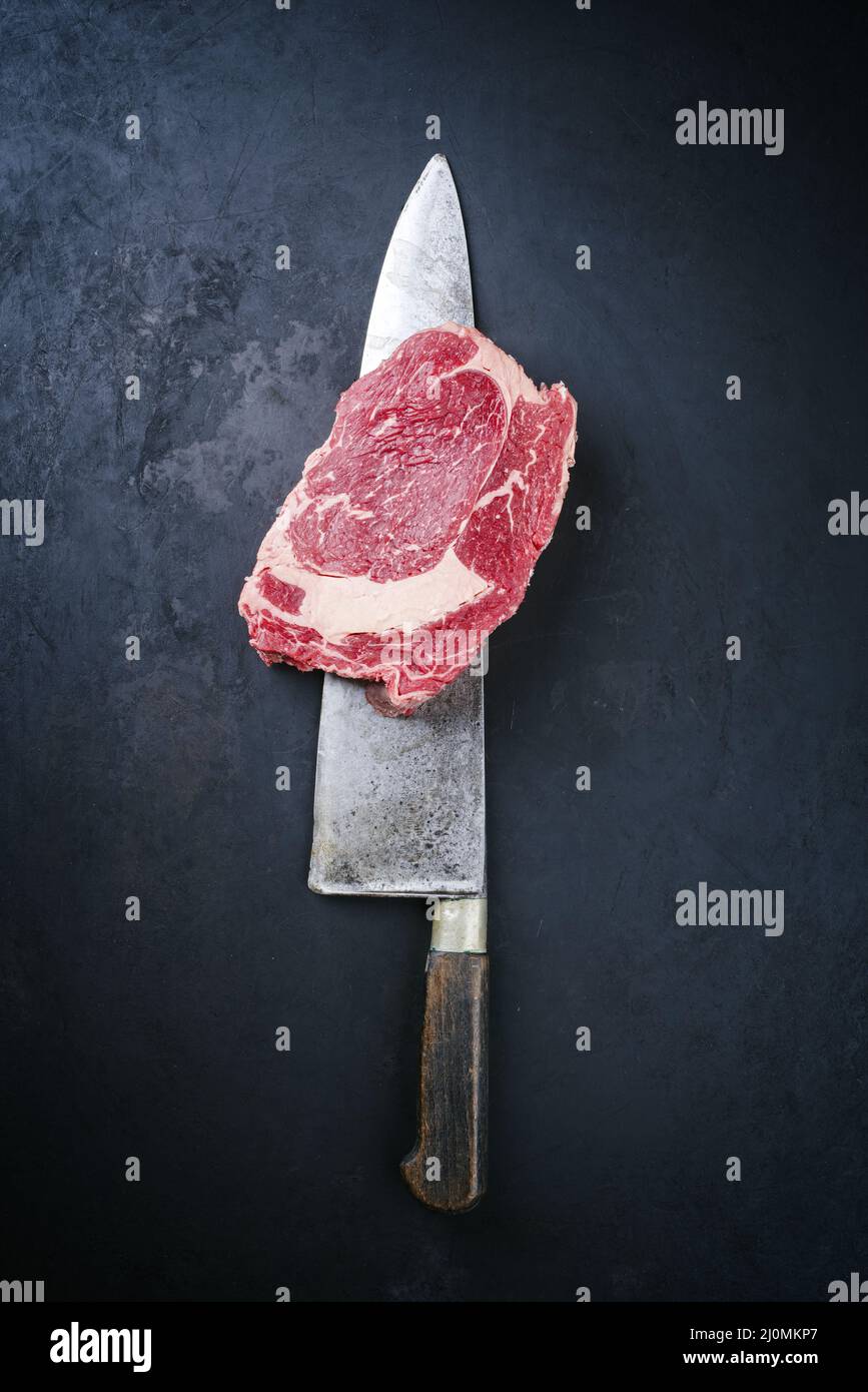 Raw dry aged wagyu rib-eye beef steaks offered as top view on a large ...